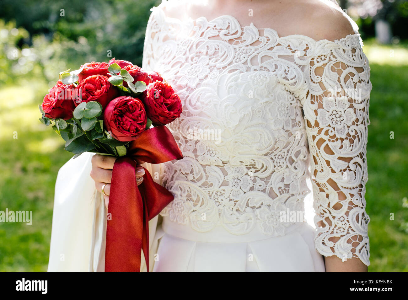 wedding bouquet of burgundy roses in the hands of the bride Stock Photo ...