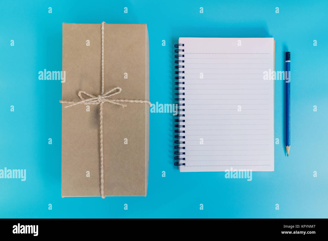 top view brown gift box and notebook paper on blue pastel color ...
