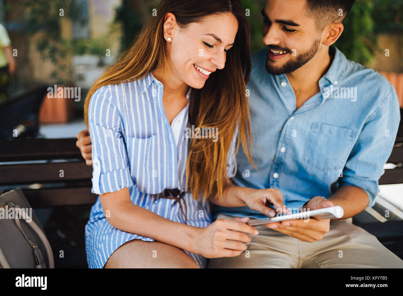 Young attractive couple on date sitting on bench Stock Photo - Alamy