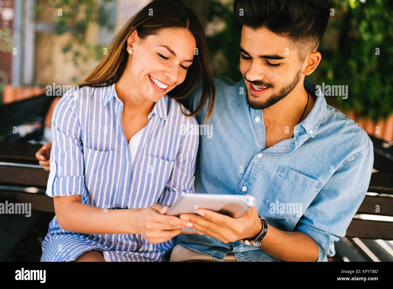 Young attractive couple on date sitting on bench Stock Photo - Alamy