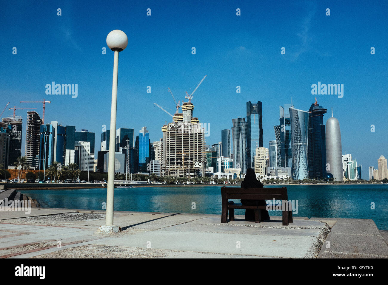Doha, Qatar - November 25, 2013. A muslim woman is sitting on a bench ...