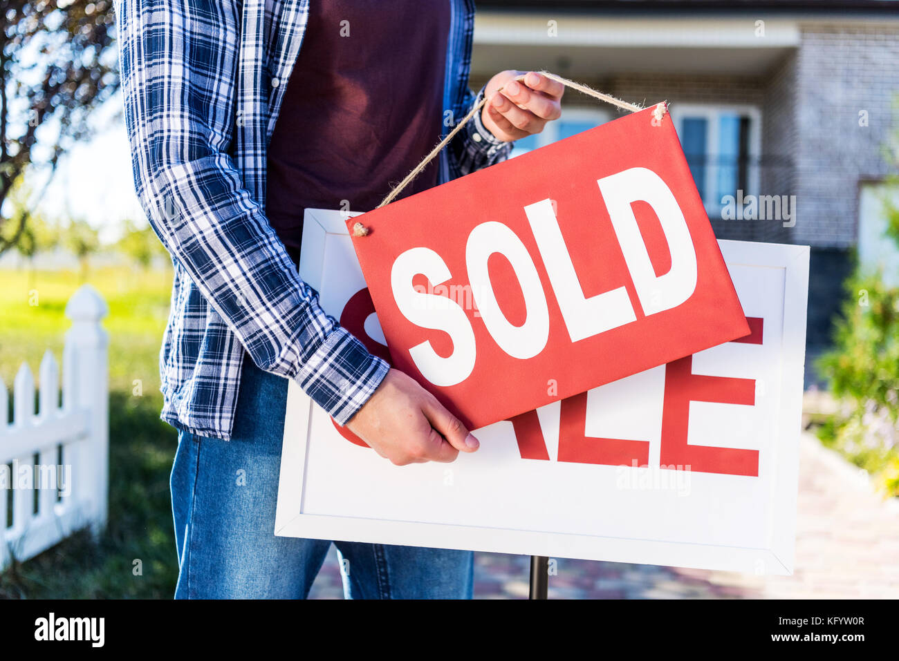 man hanging sold sign Stock Photo - Alamy
