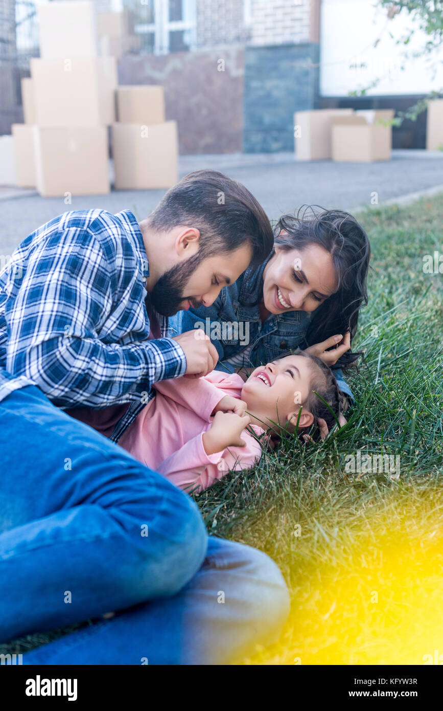 parents cuddling daughter on grass Stock Photo - Alamy