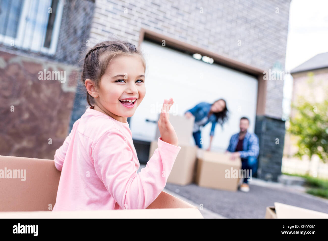 girl sitting in box and waving at camera Stock Photo - Alamy
