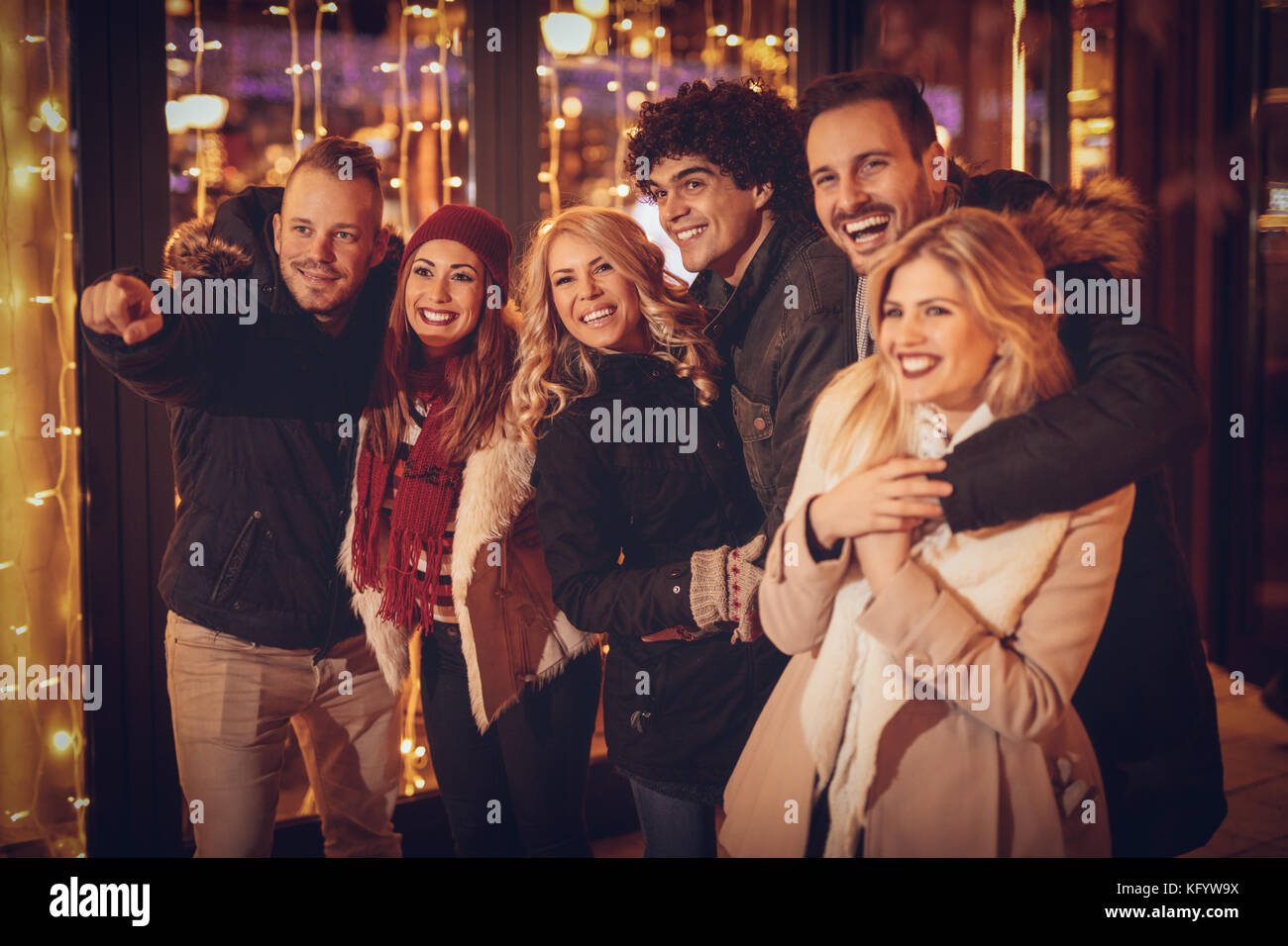 Cheerful six smiling friends having fun in city mall in Christmas night ...