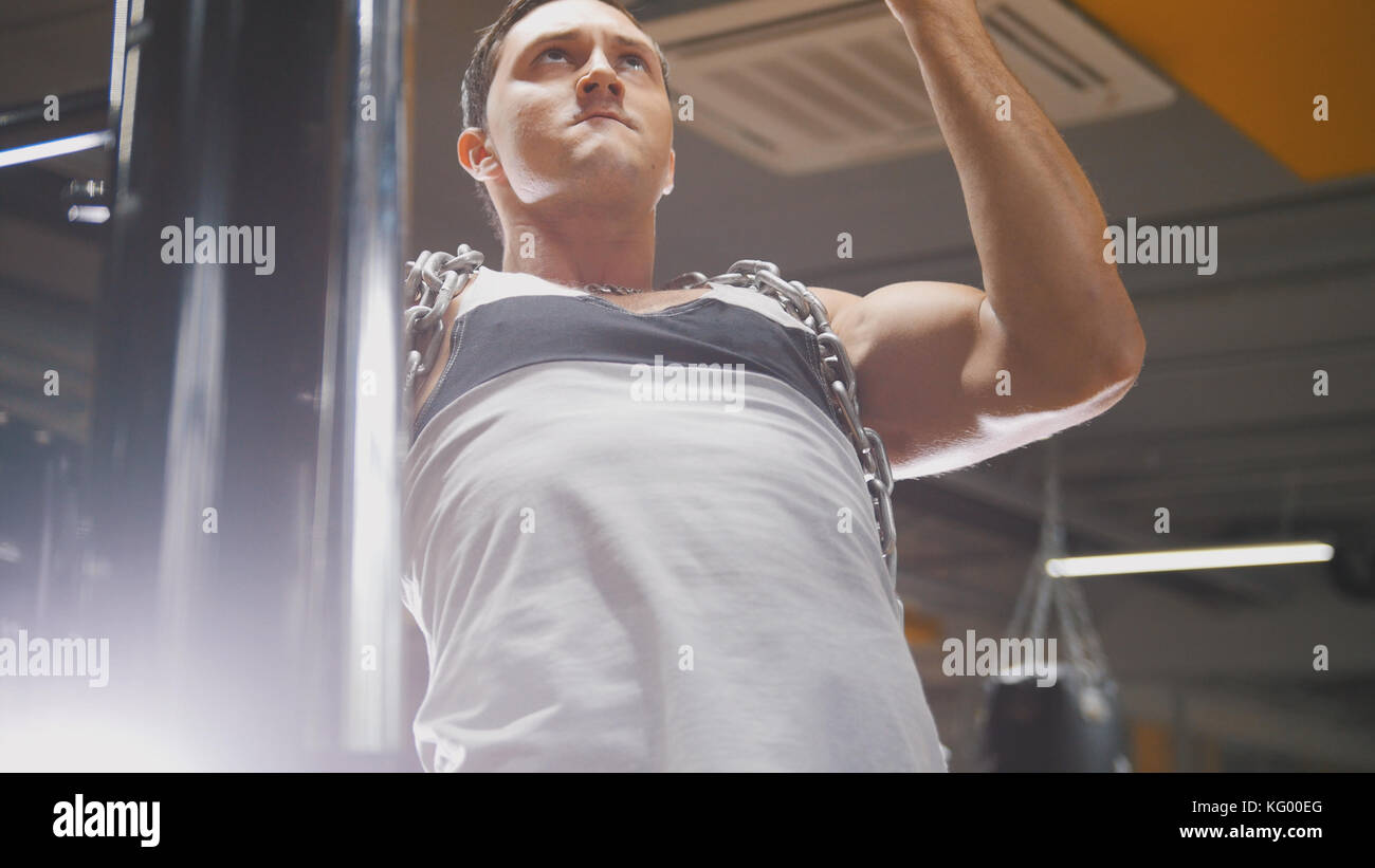 Bodybuilder - muscular man - in the gym performs pull up - close up ...
