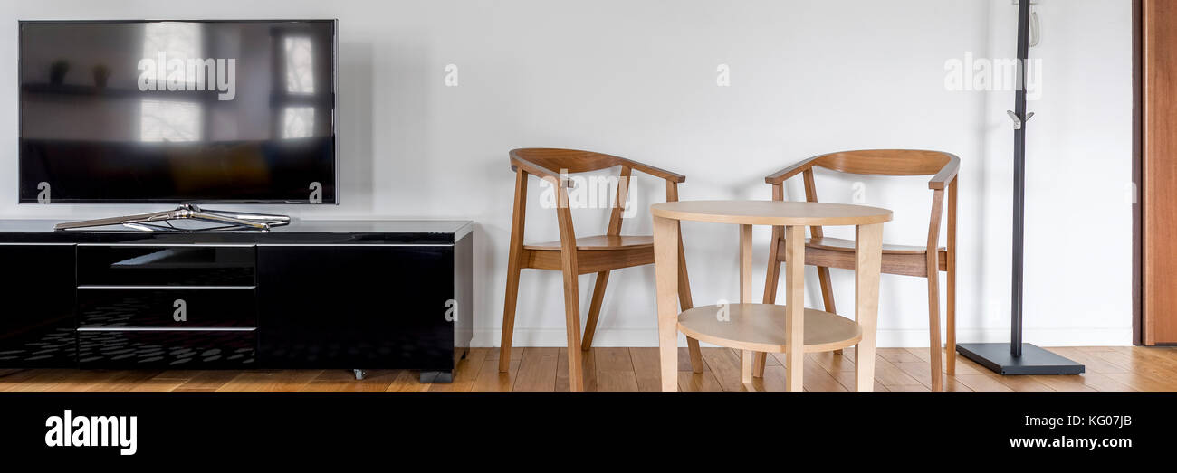 Wooden chairs and table in room with tv screen, panorama Stock Photo ...