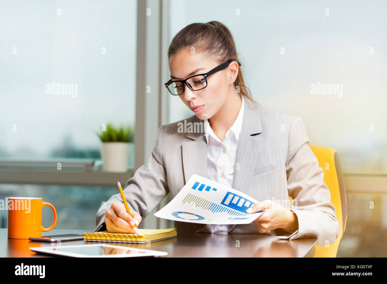 Hardworking businesswoman sitting writing a report Stock Photo - Alamy