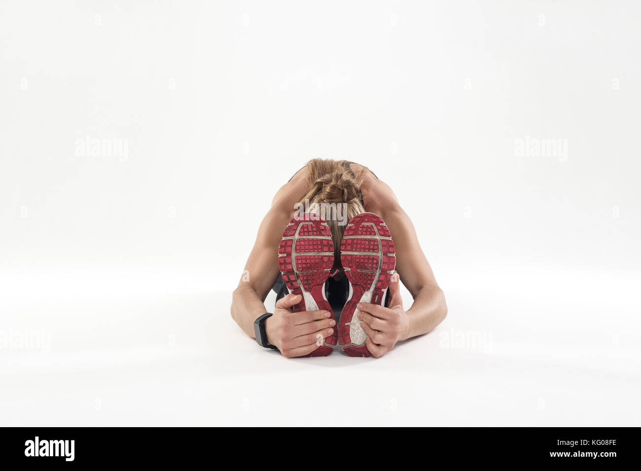 Young adult woman doing yoga, tilt forward. Studio shot, gray ...