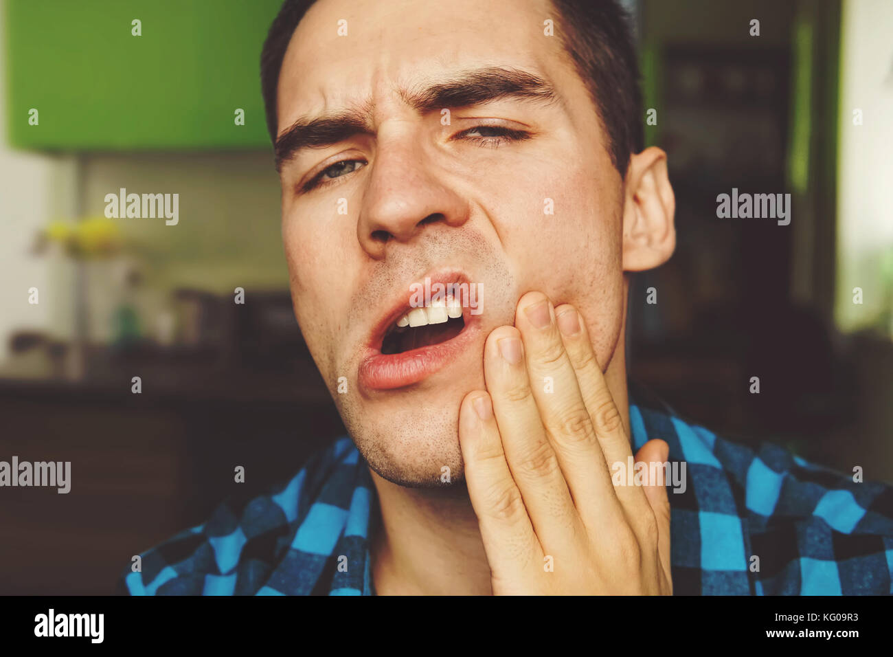 Toothache - suffering young man with teeth problems. The guy holds the ...