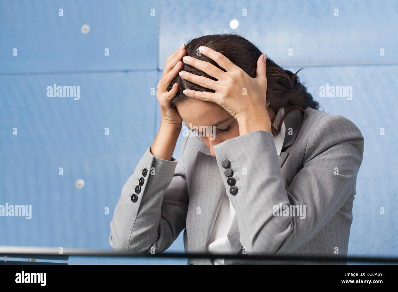 Businesswoman holding head in hands Stock Photo - Alamy