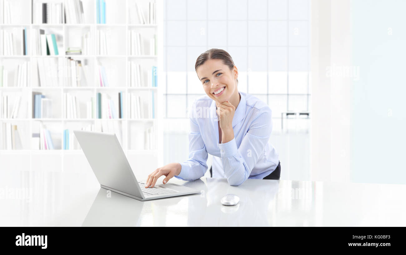 smiling woman in office with computer at desk Stock Photo - Alamy