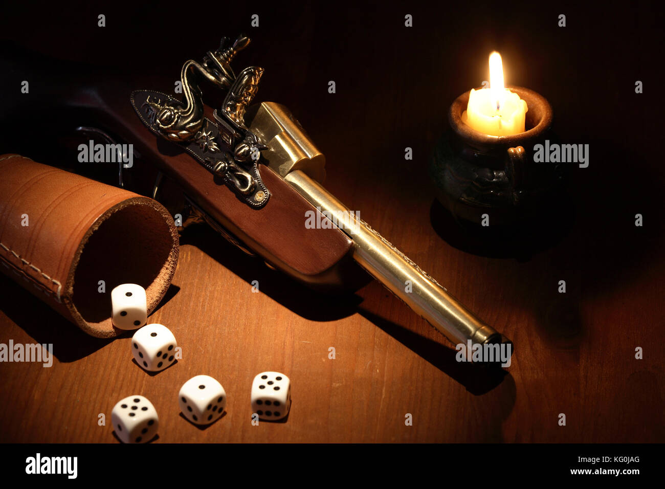 Vintage still life with old pistol and dice near lighting candle on ...