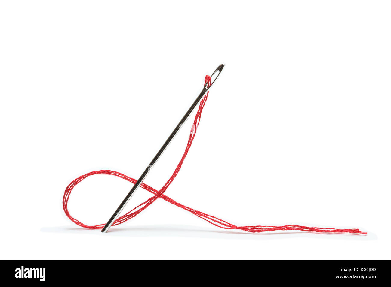 Extreme closeup of steel needle with red thread standing on white ...