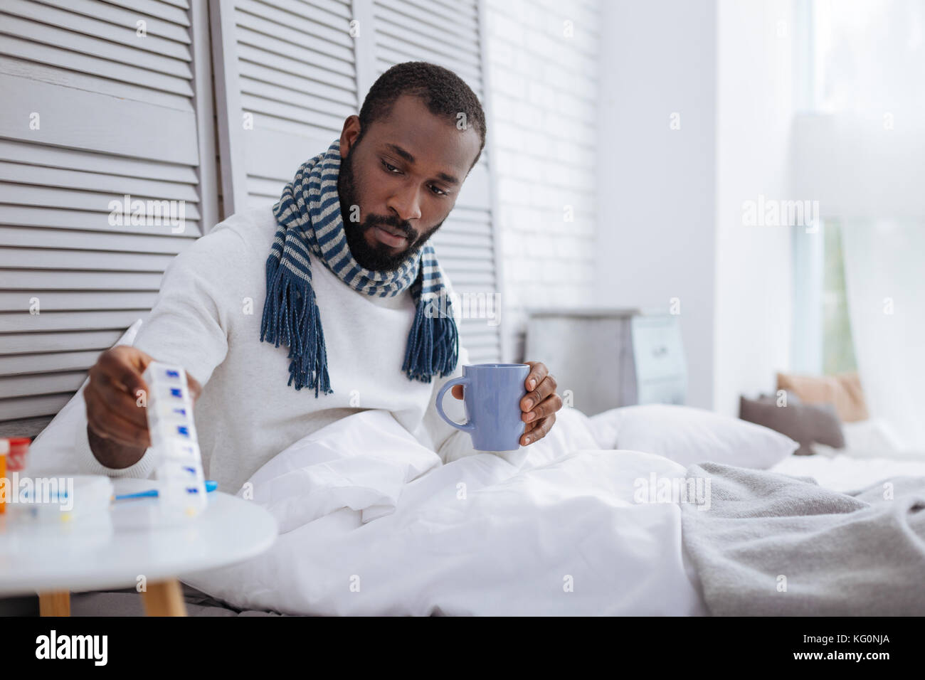 Calm man taking his pills while being ill Stock Photo - Alamy