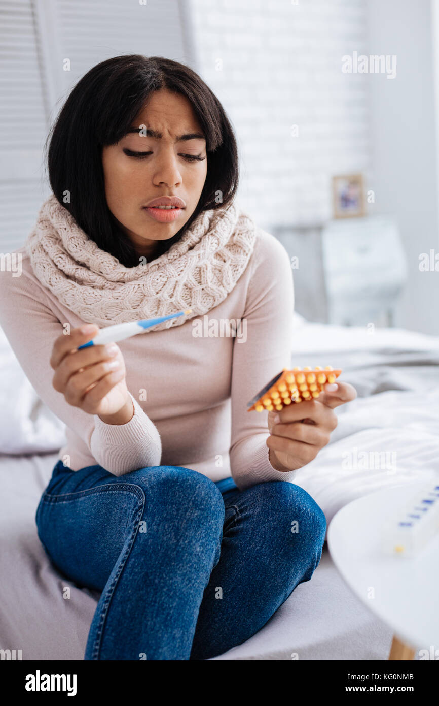 Curious attentive woman looking at the package of pills Stock Photo - Alamy