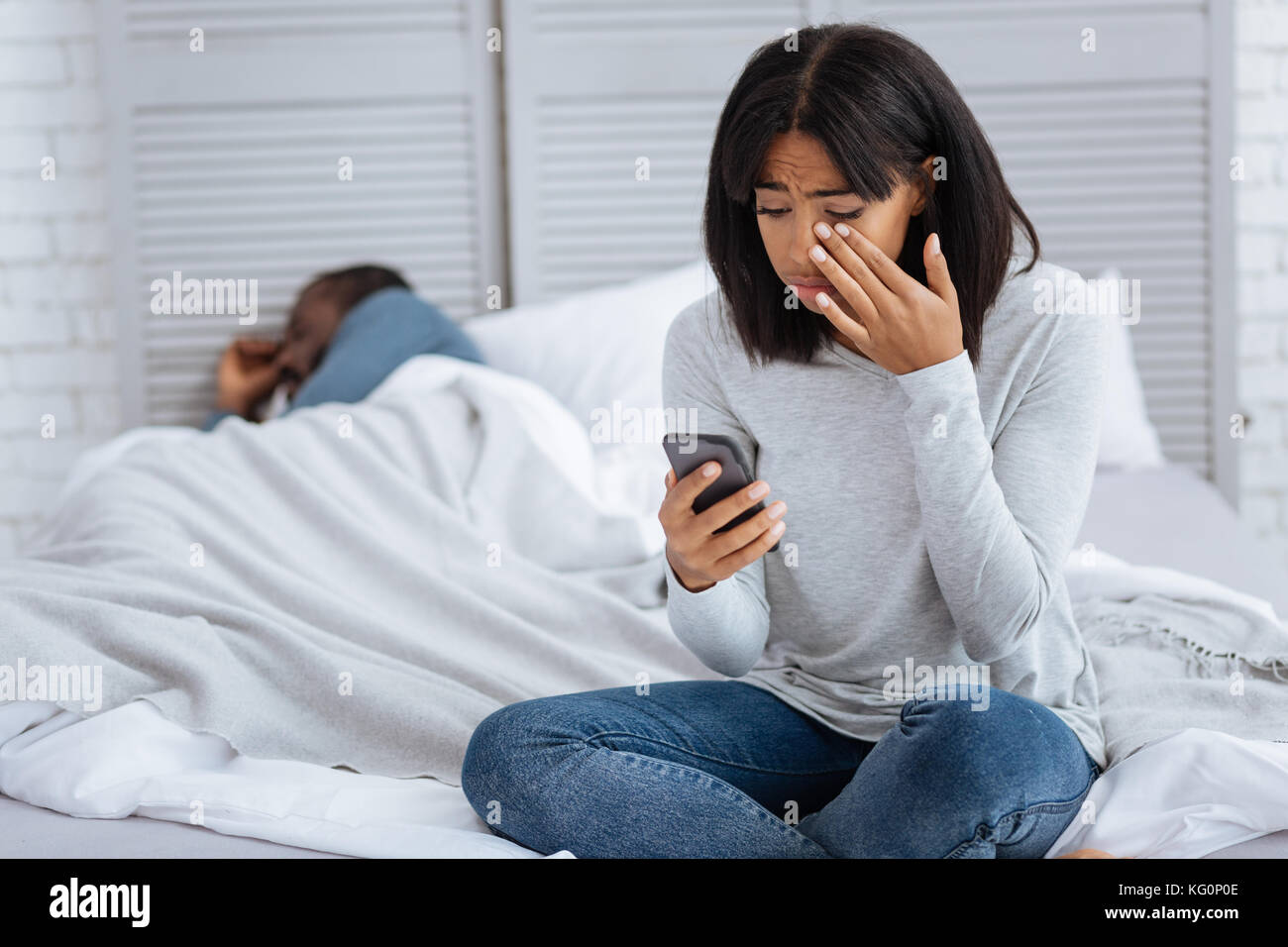Unhappy woman crying while looking at her smart phone Stock Photo - Alamy