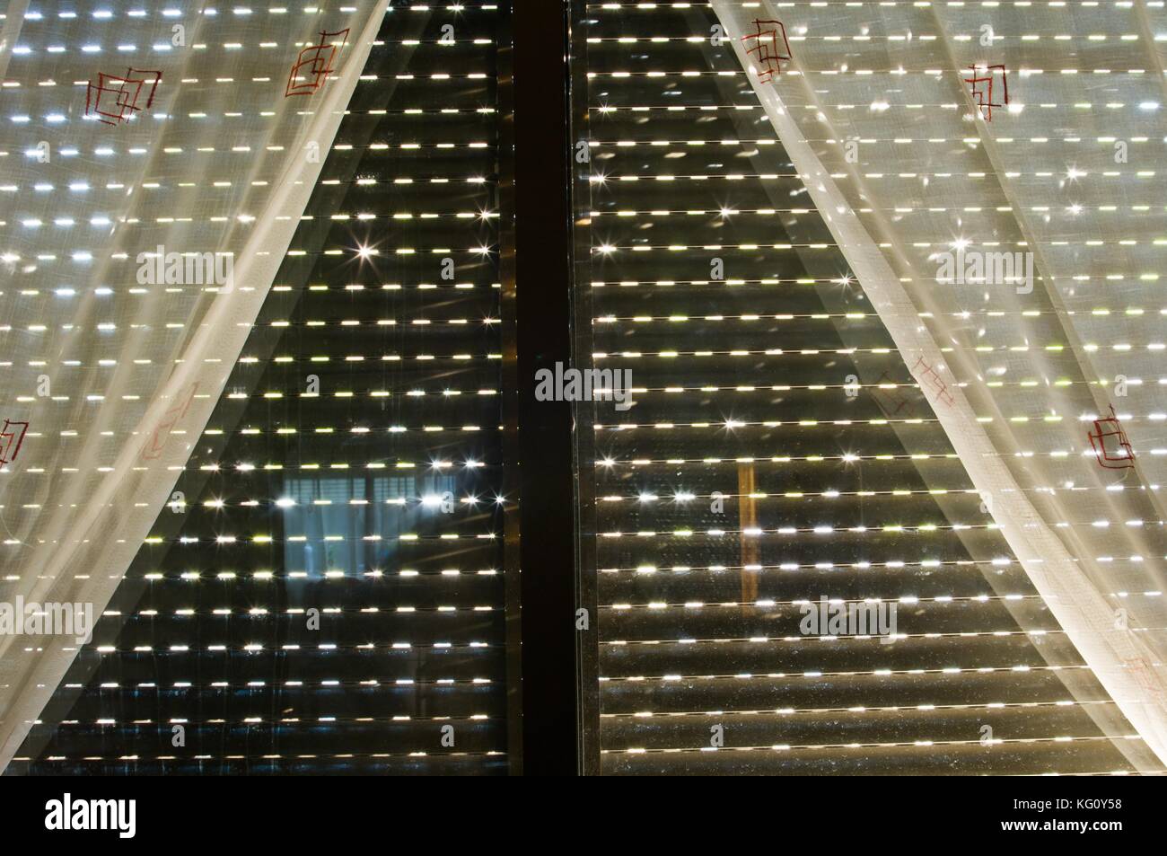 Window with curtains and blinds lowered by day entering the light of ...