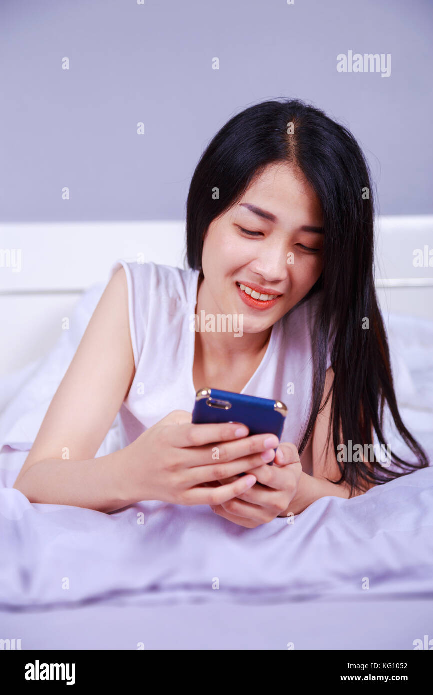 happy woman using a phone in her hand on bed in the bedroom Stock Photo ...