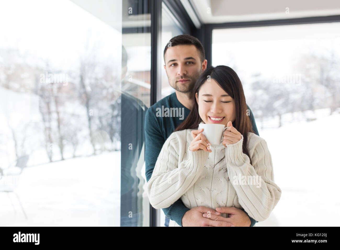 happy young multiethnic couple enjoying morning coffee by the window on ...