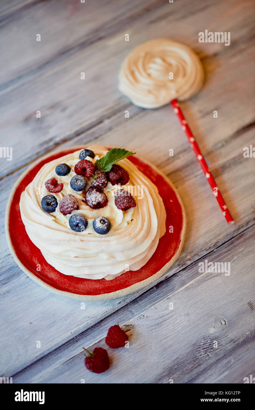 Dessert Anna Pavlova with raspberries and blueberries on white wooden ...