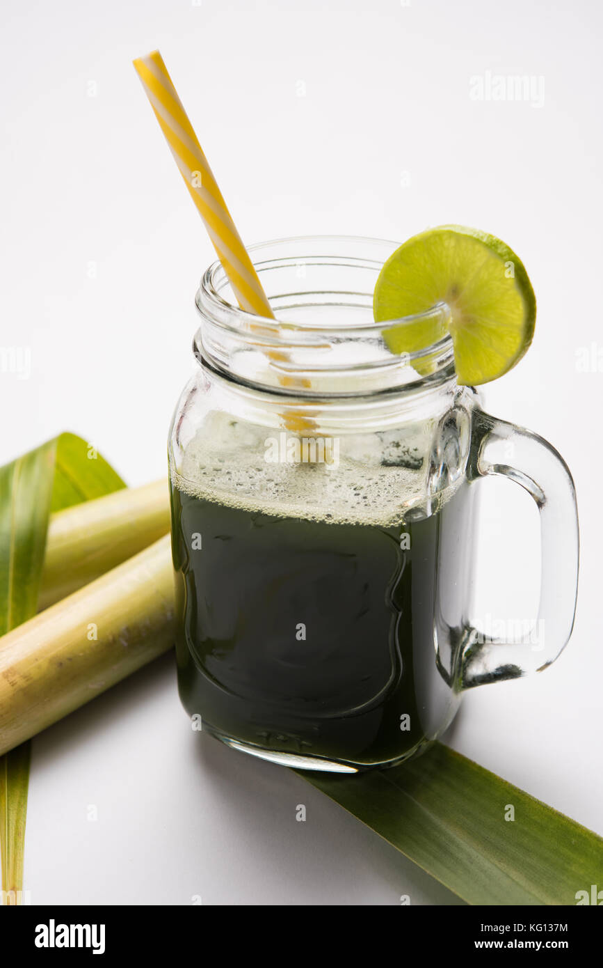 sugar cane juice or "ganne ka ras" with cut pieces cane on white ...