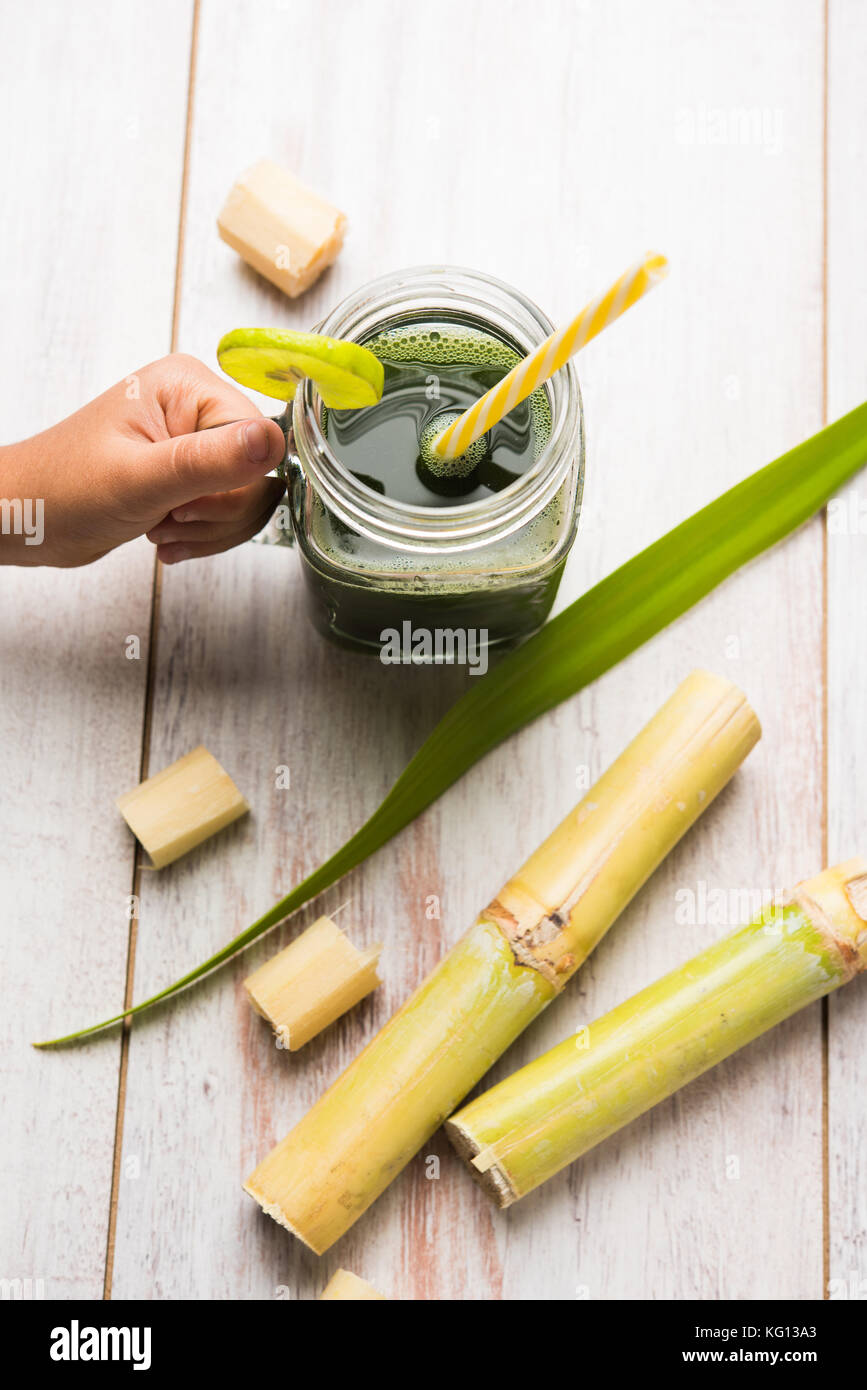 sugar cane juice or "ganne ka ras" with cut pieces cane on white ...