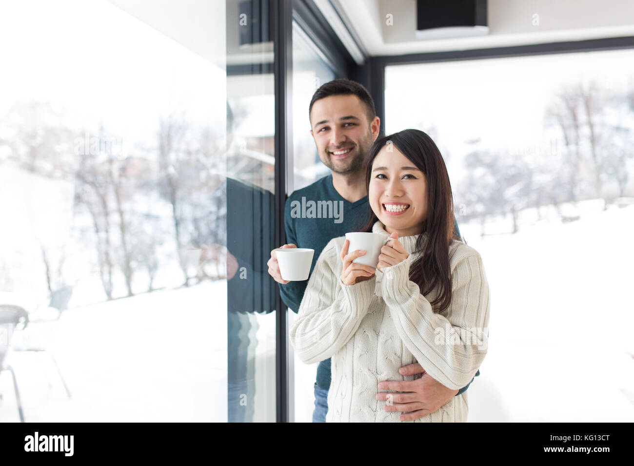 happy young multiethnic couple enjoying morning coffee by the window on ...