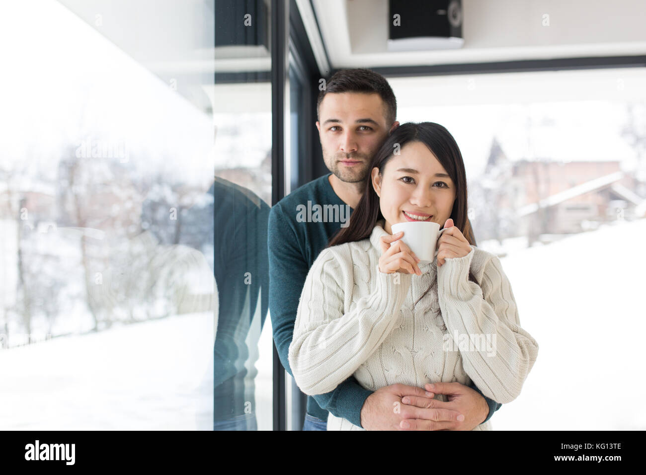 happy young multiethnic couple enjoying morning coffee by the window on ...