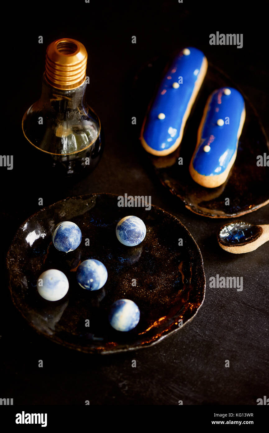 Blue eclairs and candy in blue colors. On a dark background. Pastry ...