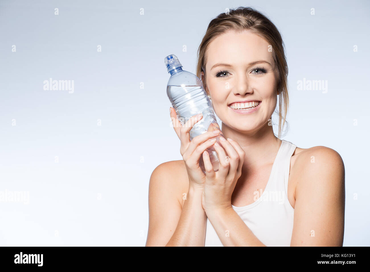 Female fitness model holding a water bottle in a white studio ...