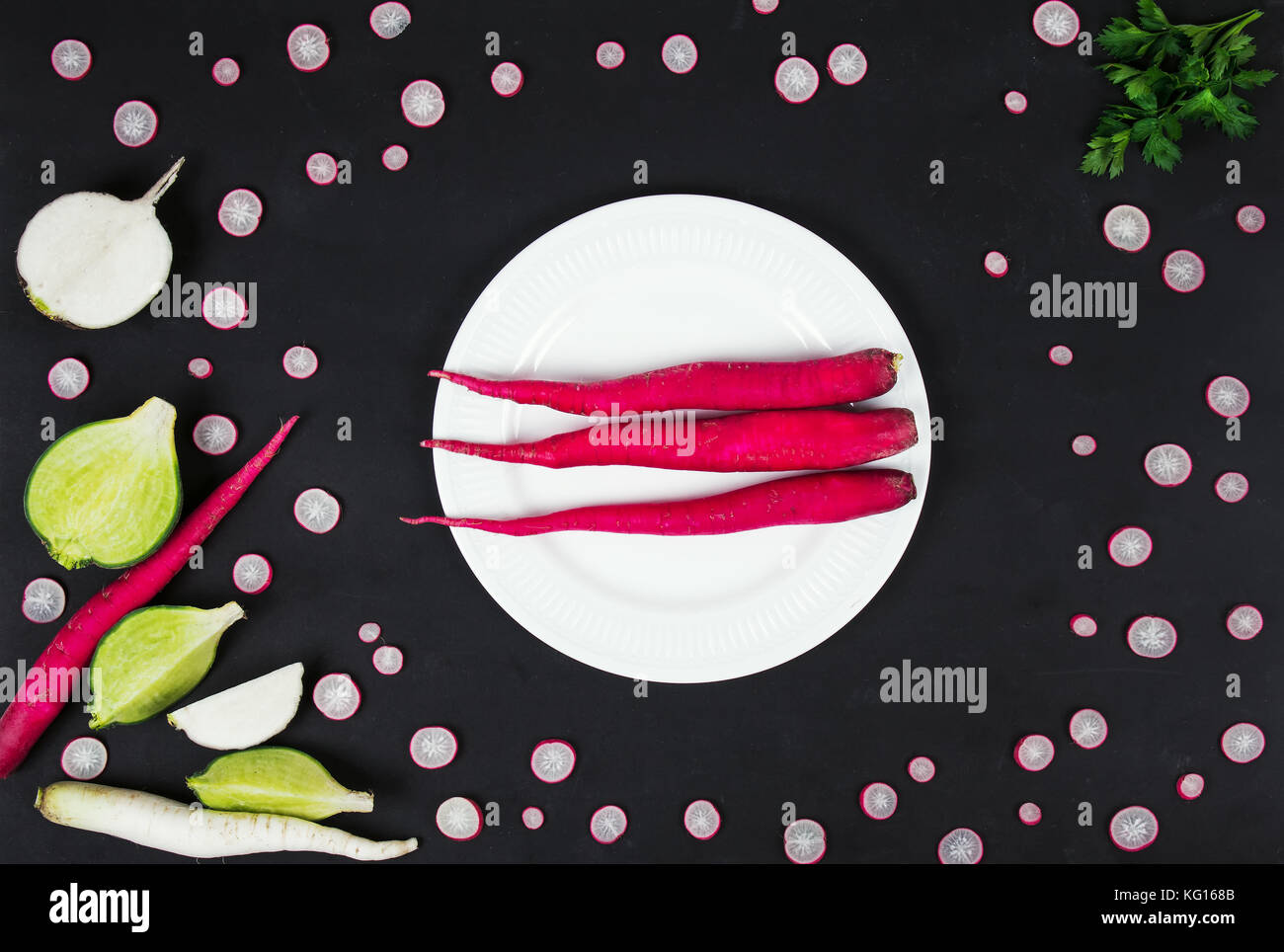radish on a plate of long pink, on a black background vegetables Stock ...