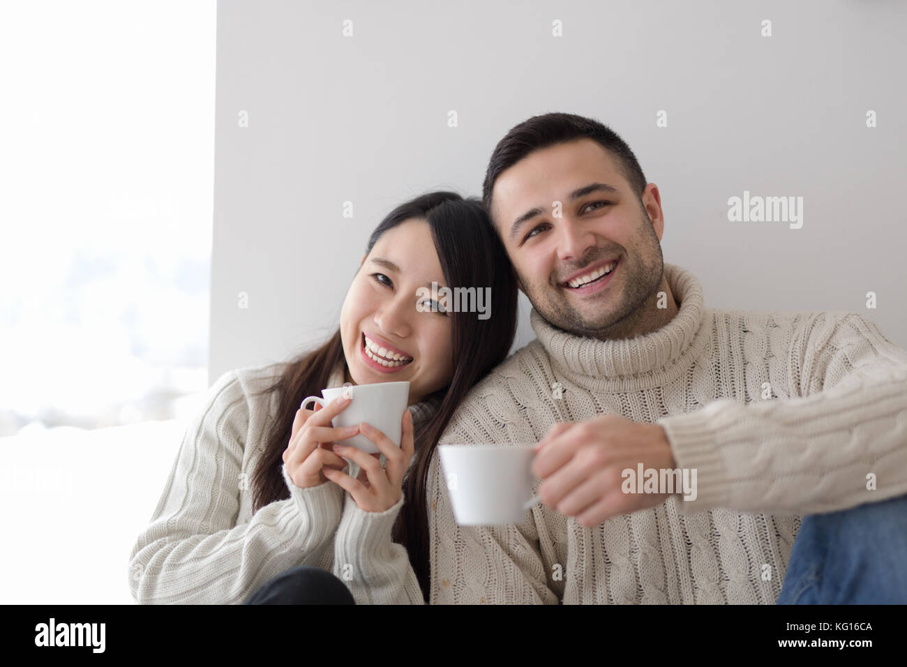 happy young multiethnic couple enjoying morning coffee by the window on ...