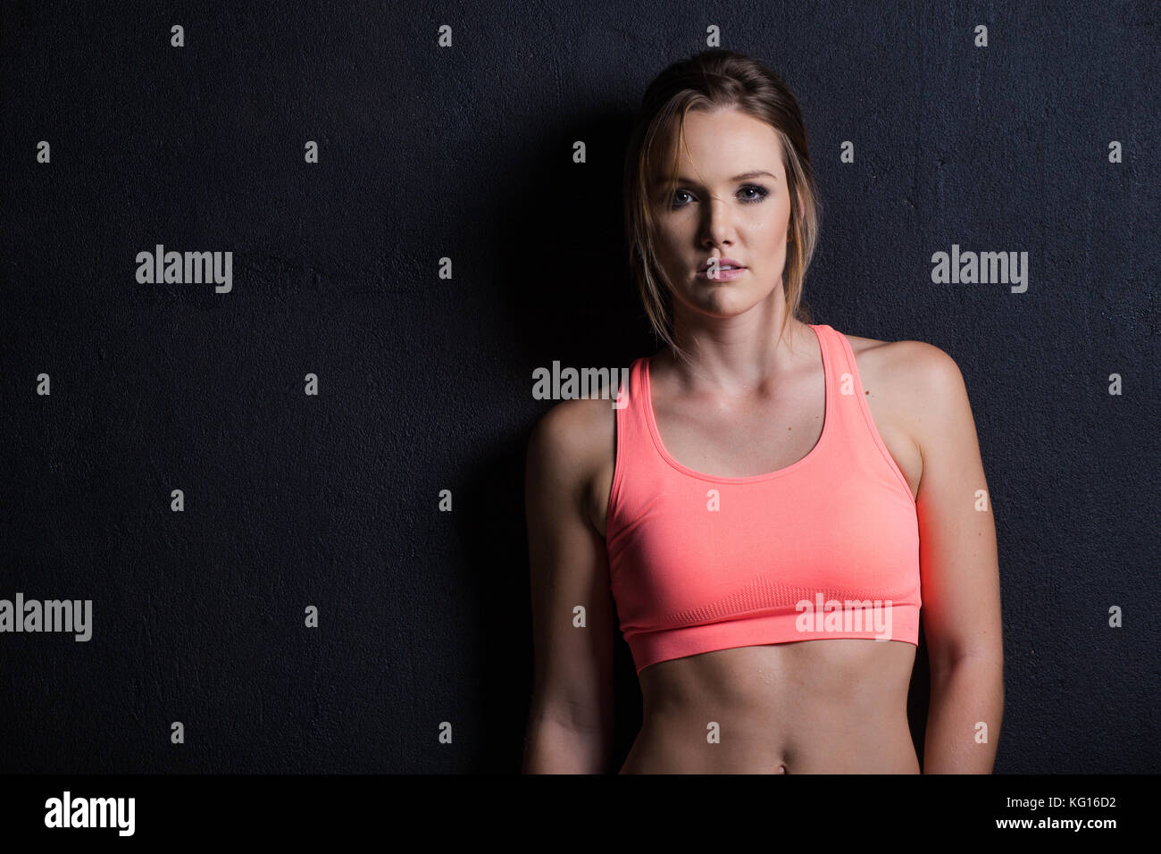 Beautiful female fitness model holding her towel/weights in a dark ...
