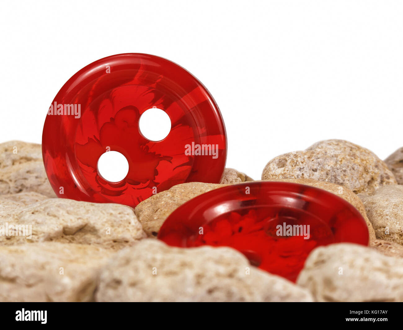 Bright red buttons among stones white background Stock Photo - Alamy