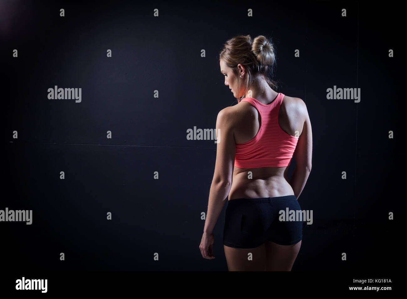 Beautiful female fitness model holding her towel/weights in a dark ...
