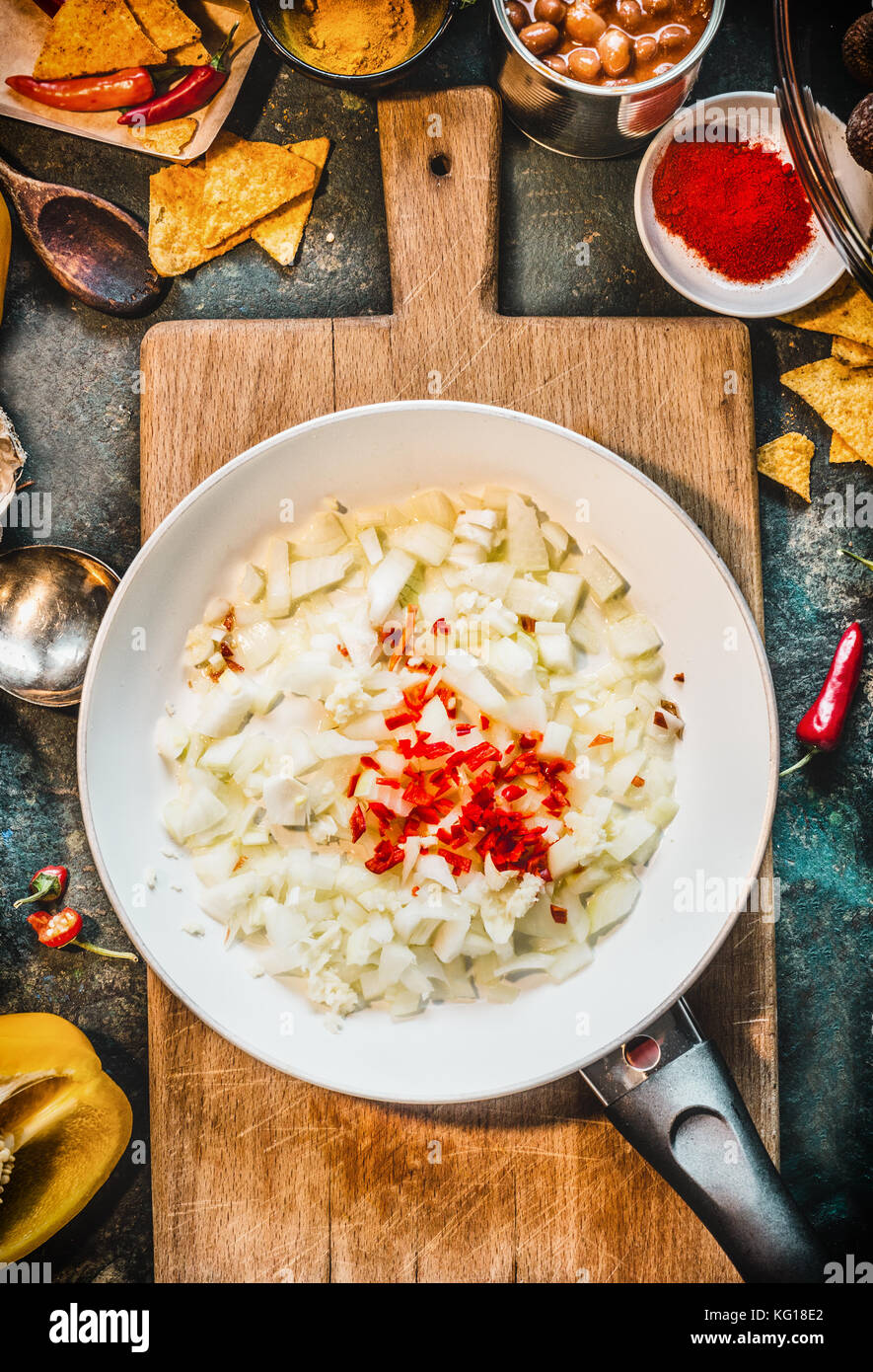 Spicy food cooking preparation. Frying pan with cut onion, garlic and ...