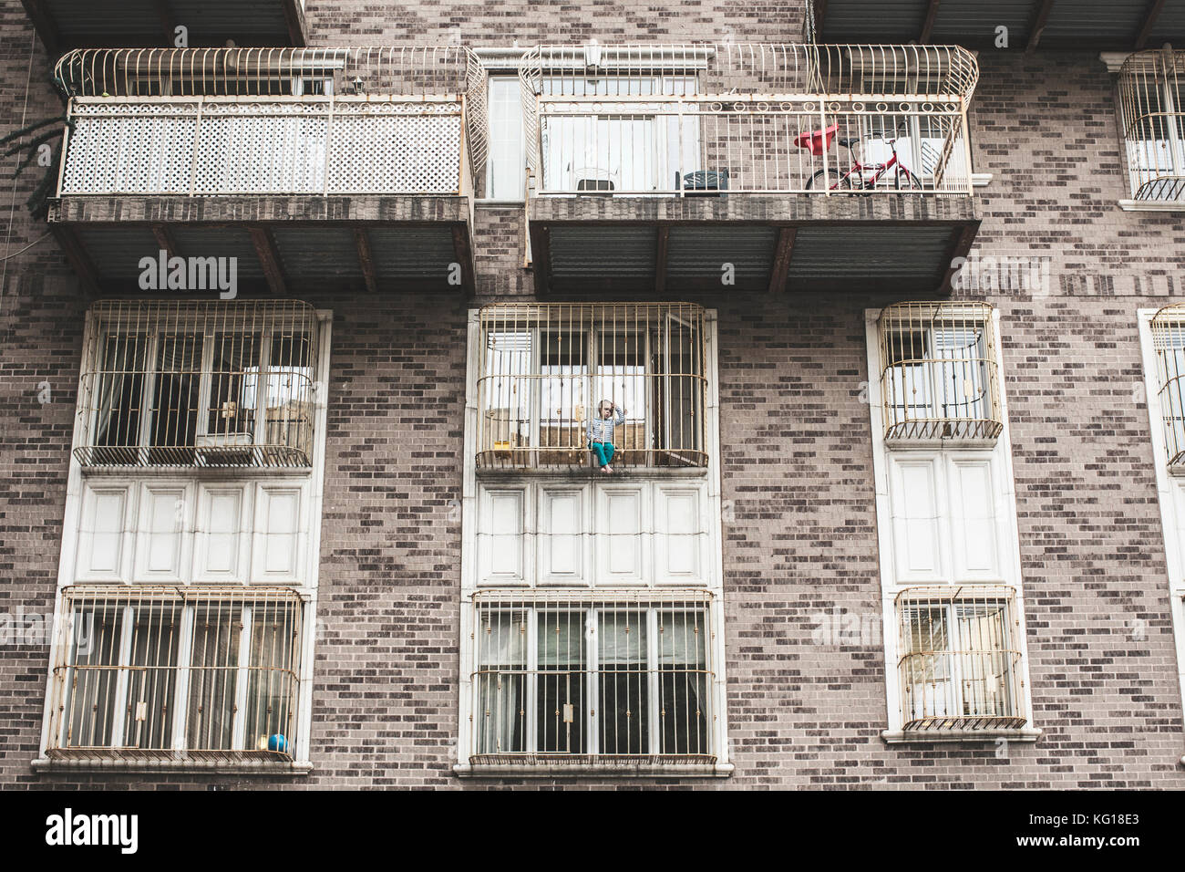 A kid is sitting alone on a balcony in New York, United States of ...