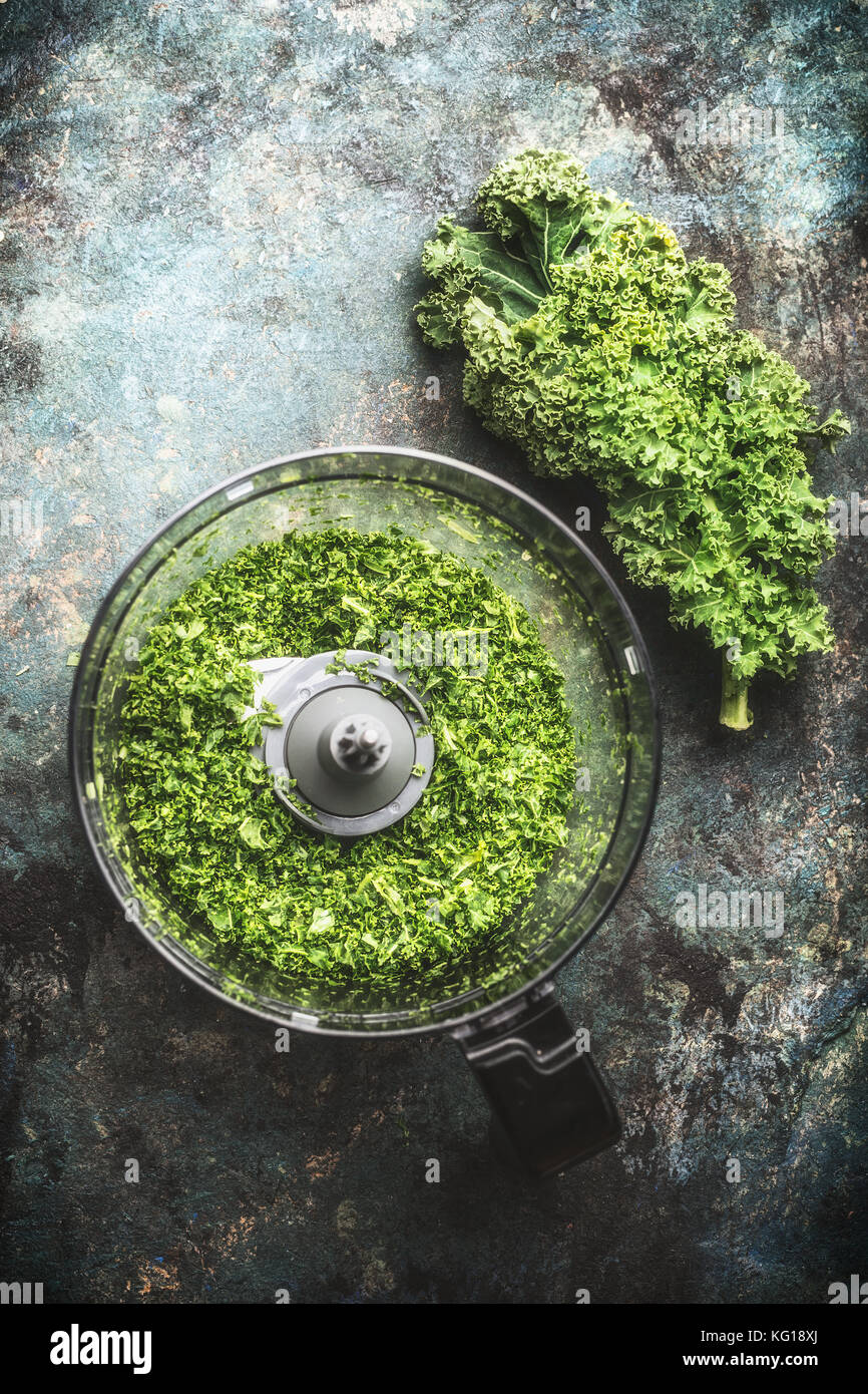 Chopped green kale leaves in chopper on rustic background, top view ...