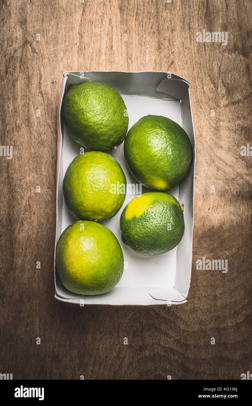 Fresh green lime in paper box on rustic wooden background, top view ...