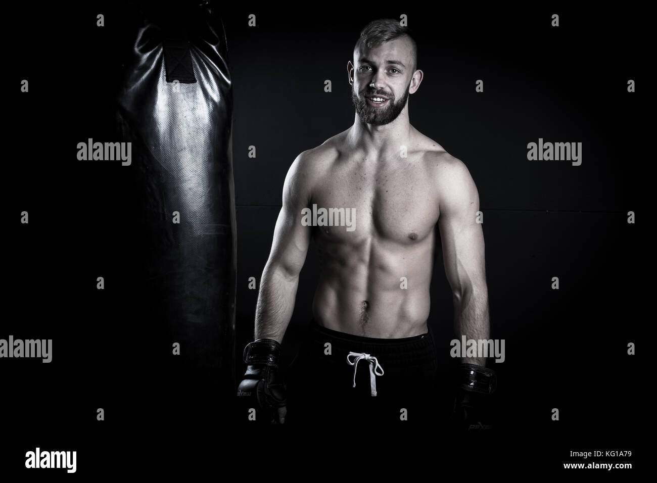 Male Athlete boxer punching a punching bag with dramatic edgy lighty in ...