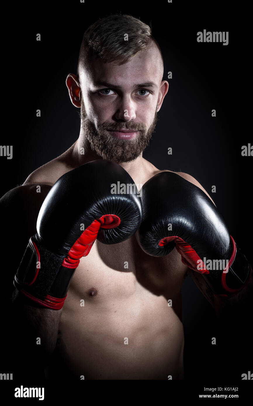 Male Athlete boxer punching a punching bag with dramatic edgy lighty in ...