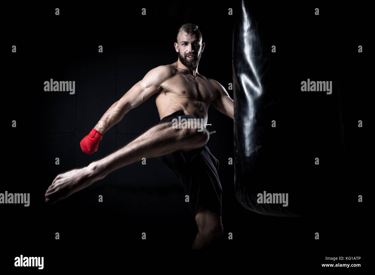 Male Athlete boxer punching a punching bag with dramatic edgy lighty in ...