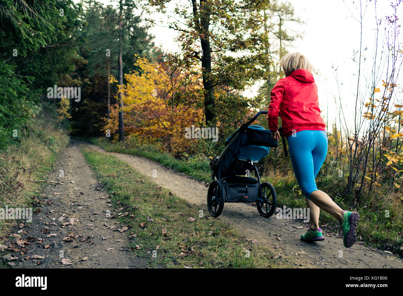 Running mother with child in stroller enjoying motherhood at autumn ...