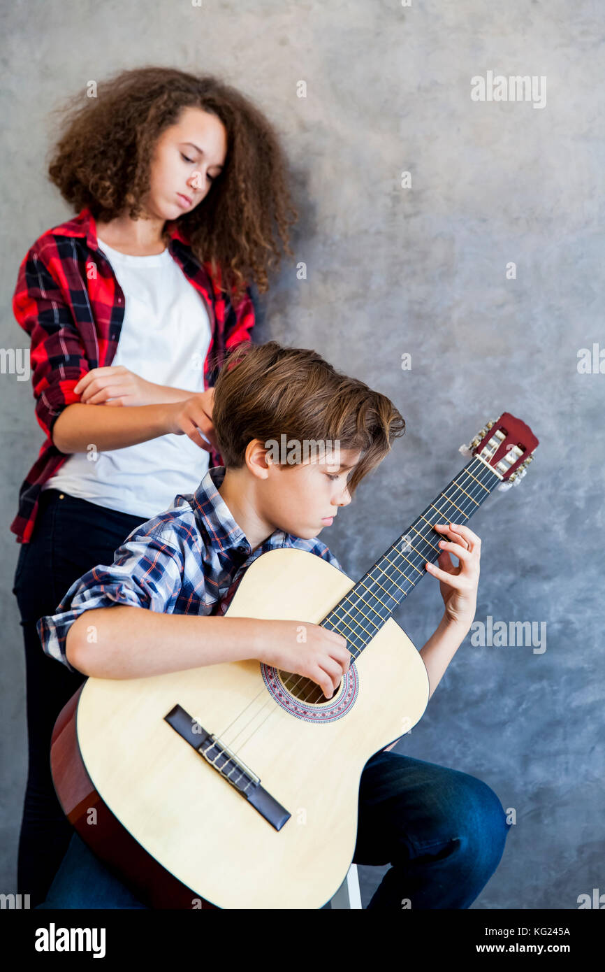 Teen boy playing acoustic guitar while teen girl listening him in the ...