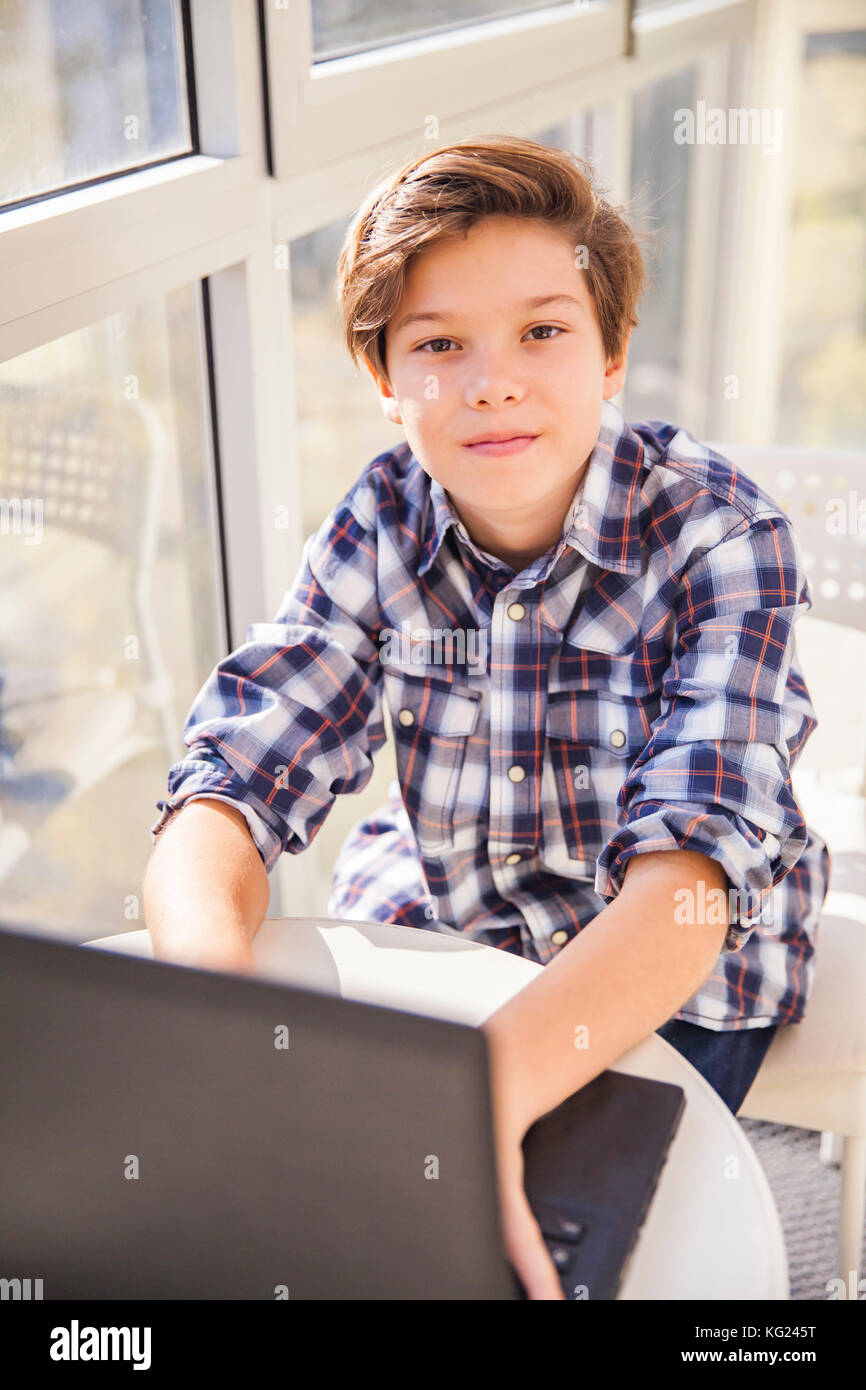 Portrait of teen boy using laptop by window Stock Photo - Alamy