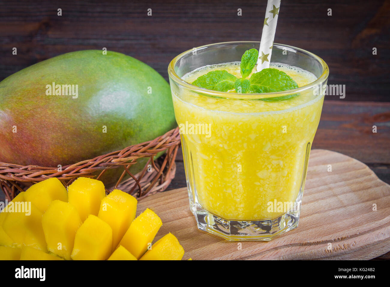 Smoothies mango with straw and mint in a glass beaker. Plate with ...