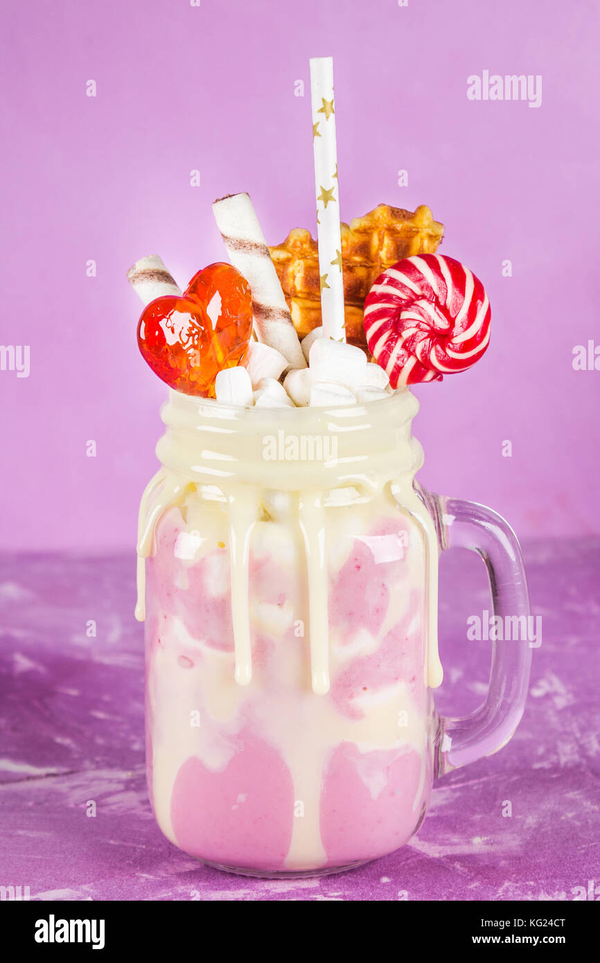 Freakshake from pink smoothie, cream. Monstershake with lollipops ...