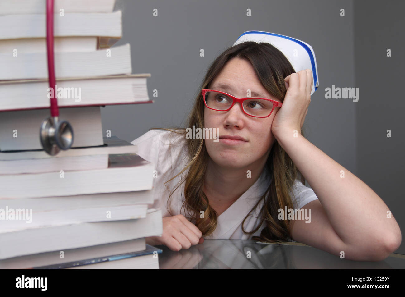 Young bored and tired female nurse portrait wearing white scrubs, cap ...