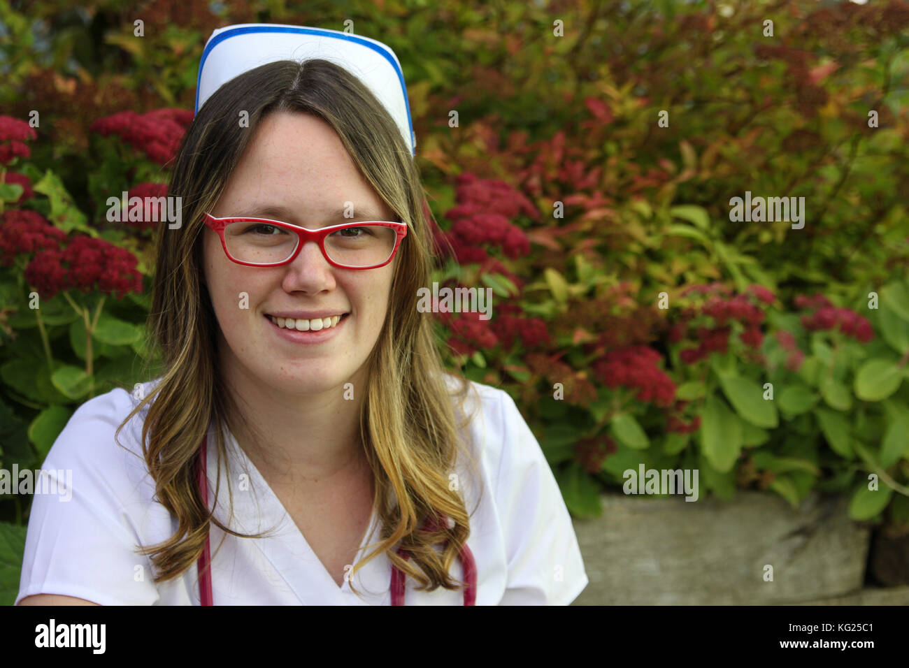 Young smiling female nurse portrait wearing white scrubs, cap and a ...